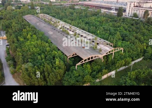 Old destroyed construction with holes in roof and overgrown with around ...