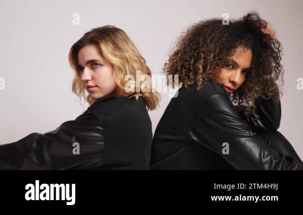 Two young women with different appearance features sitting back to back ...