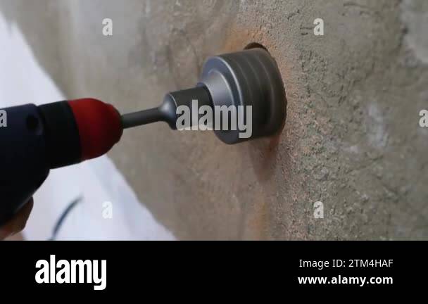 Installation of socket boxes in a brick wall. A male worker is drilling ...