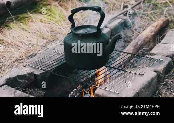Kettle over the fire. An old vintage smoked teapot is boiling water ...