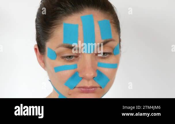 Young woman applied light blue kinesio strips taping face, forehead ...