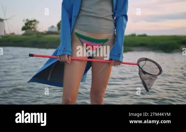 Fishing woman standing river in evening closeup. Slim female body with scoop net. Unrecognized ...