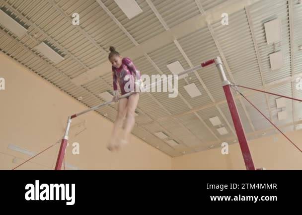 Acrobatic little girl in purple leotard practicing artistic elements on ...
