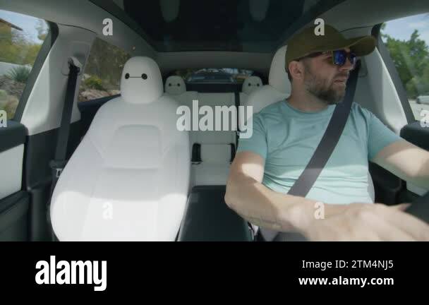 Mature male driver inside Tesla Model Y car using self drive autopilot ...