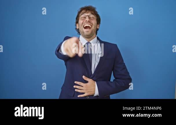 Young blonde guy in business suit has a laugh on you, pointing finger ...