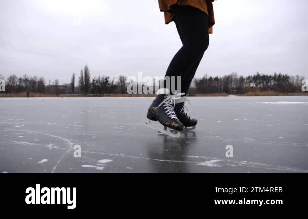 Legs of woman shod in figure skates sliding on ice surface at nature ...