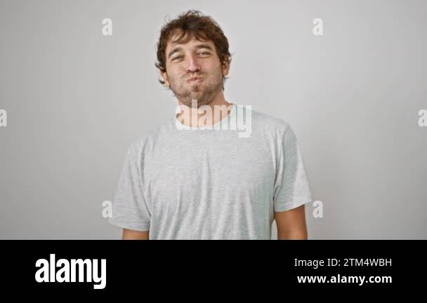 Cheeky young guy in a t-shirt making a hilarious grimace, puffing ...
