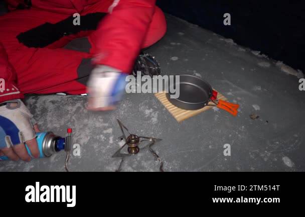 A guy cooks food on gas inside an ice cave. The climber lights the ...