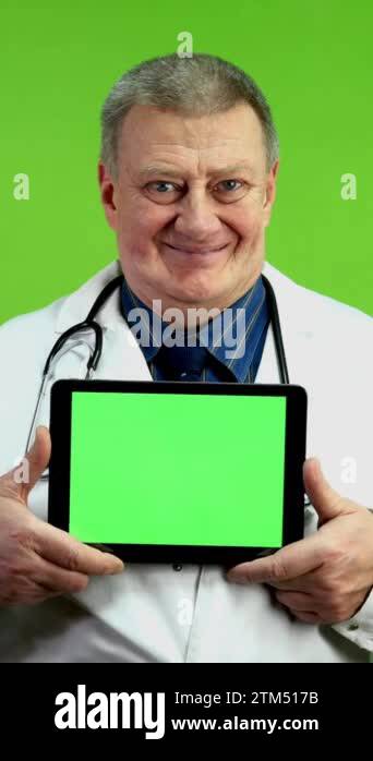 Smiling senior doctor holds digital tablet for medical news or ...