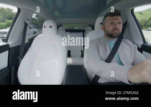 Mature male driver inside Tesla Model Y car using self drive autopilot ...