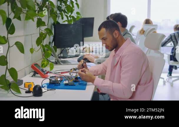 Multiracial Handsome Guy Engineer Resolders Parts of Motherboard in ...