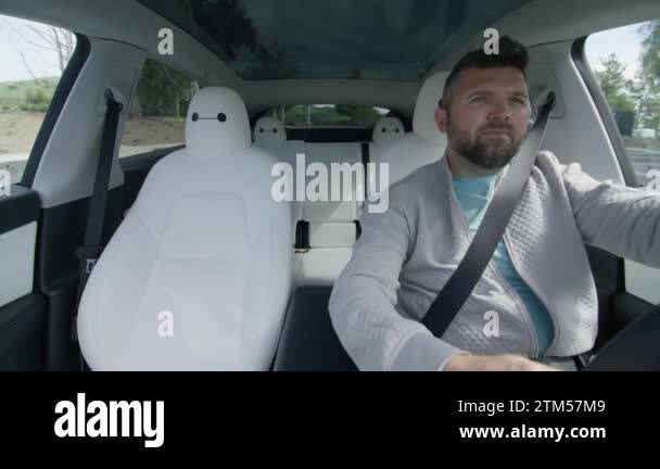 Mature male driver inside Tesla Model Y car using self drive autopilot ...