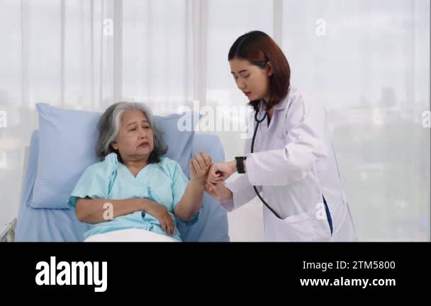 Medium shot, A young female doctor checks the heart rate of an elderly ...