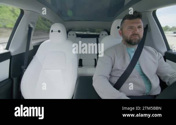 Mature male driver inside Tesla Model Y car using self drive autopilot ...