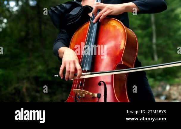 Cello in woman's hands outdoors. Beautiful woman with earrings and ...