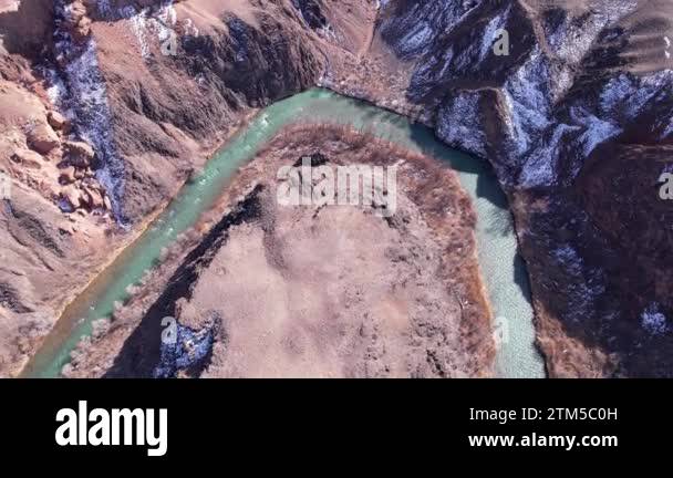 A long river with green water in the Charyn Canyon. There is white snow ...