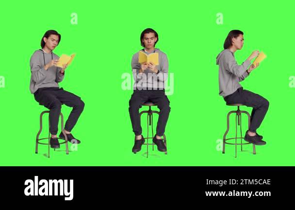 Trendy person reading novel book on chair against full body greenscreen ...