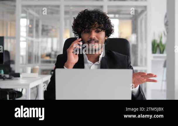 Busy handsome Indian man is seen multitasking in office male talks on ...