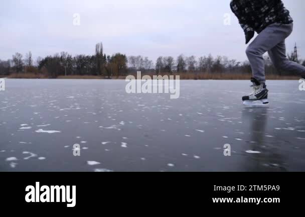 Young man in figure skates sliding fast on ice during training. Guy ...