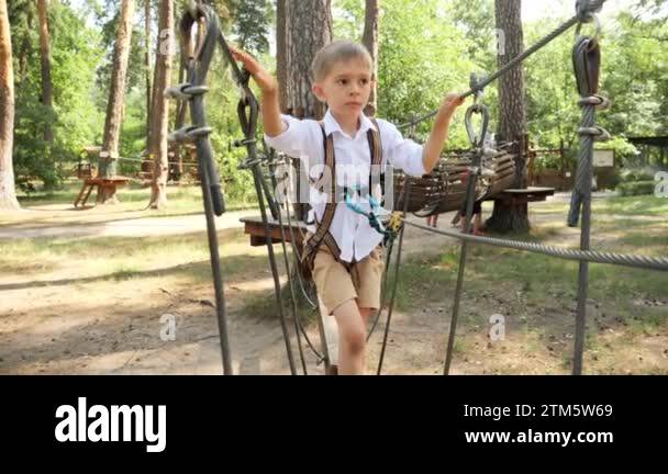 Little boy walking over rope bridge at outdoor amusement park. Active ...
