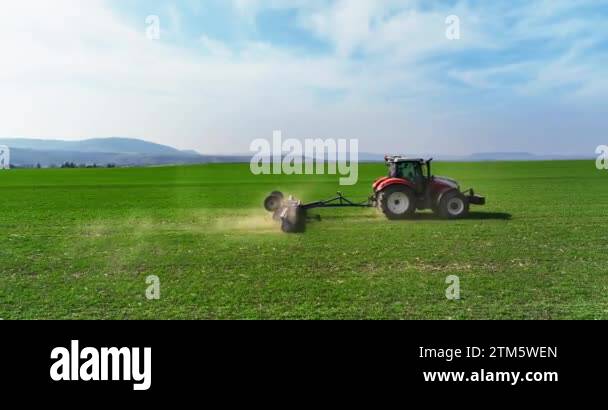 Tractor with a roller tillage on spring field, aerial 4k video. Soil ...