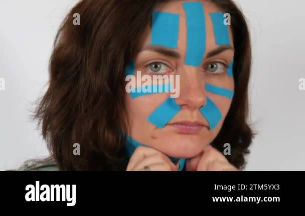 Young woman applied light blue kinesio strips taping face, forehead ...