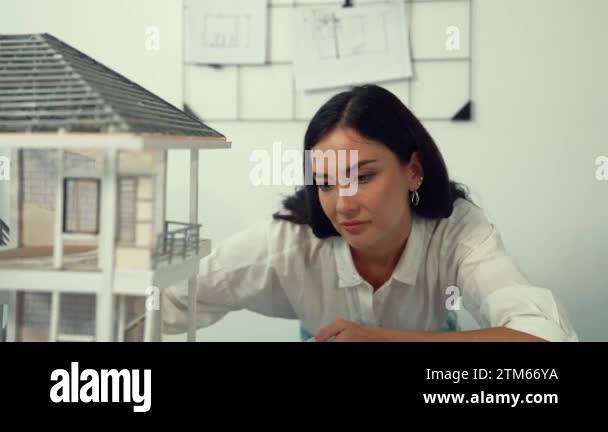 Young beautiful caucasian architect engineer turns house model around ...