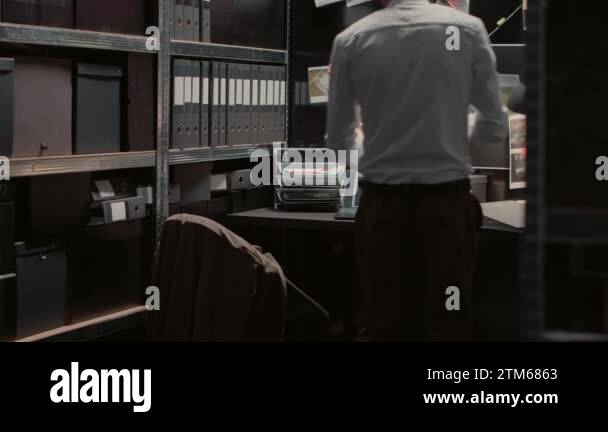 Detective sitting at desk analyzing evidence map on wall, examining law ...