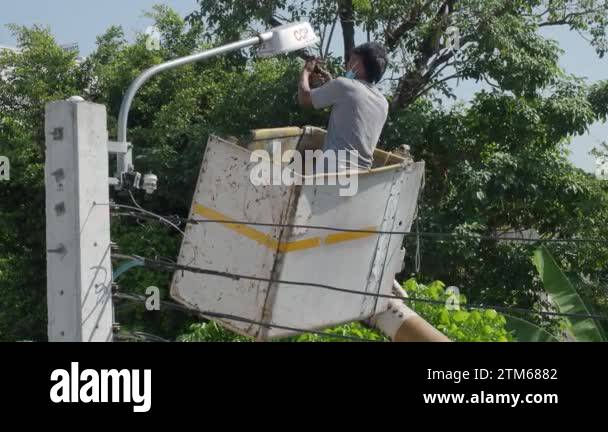 Worker on height lifting platform installing new street light bulb ...