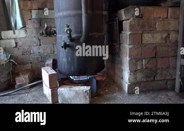 Alcohol distillation apparatus and drink flow into jar in peasant hand ...
