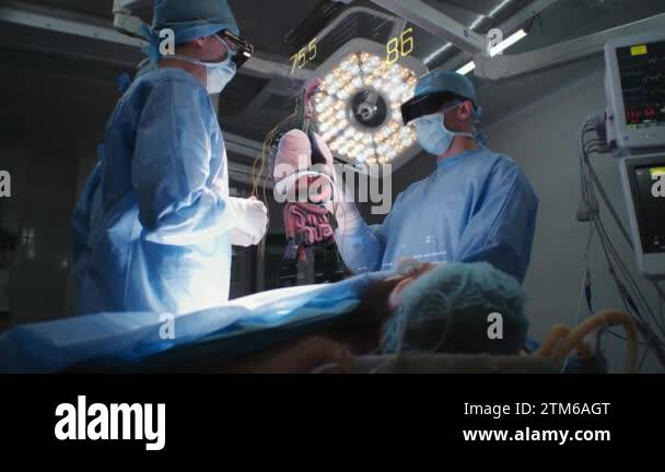 Doctors perform surgery in hospital operating room in VR headsets. 3D ...