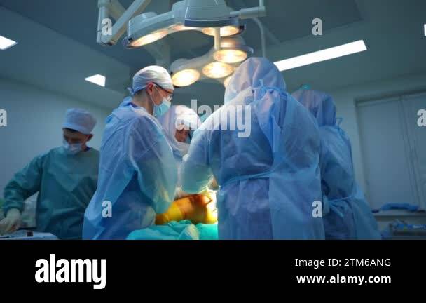 Operating theater. Team of doctors doing a surgery to a patient lying ...