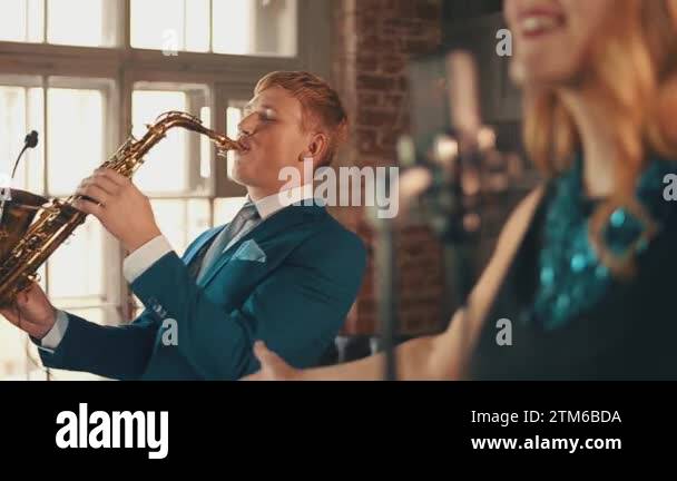 Jazz vocalist in glare dress performing on stage with saxophonist ...