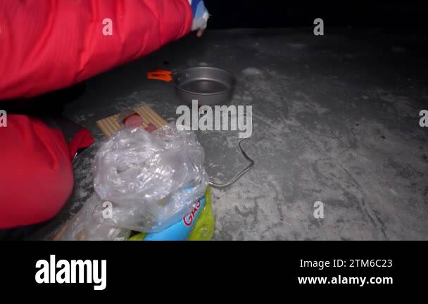 A guy cooks food on gas inside an ice cave. The climber lights the ...