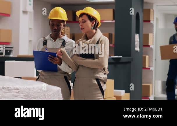Two supervisors counting boxes of stock merchandise in storage room ...