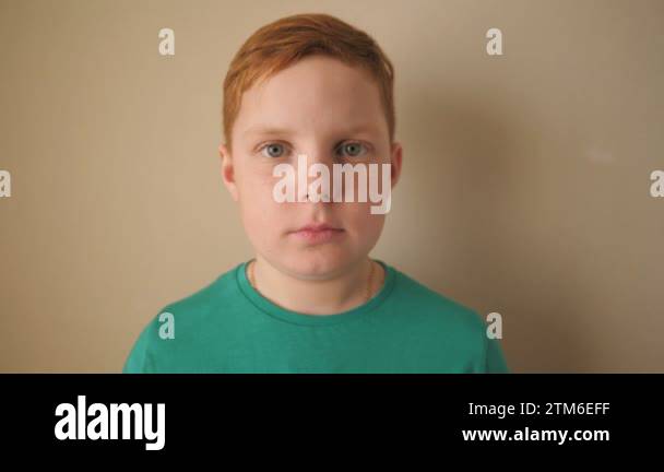Portrait of little serious red-haired boy with freckles indoor. Unhappy ...
