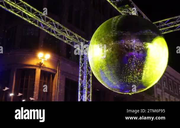 Disco Ball in the street rotates and reflects yellow and green light at ...
