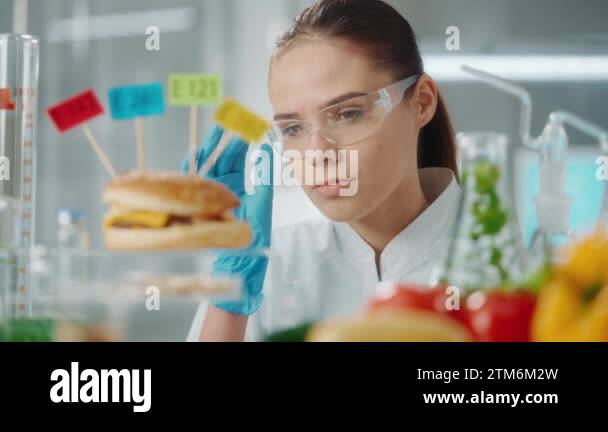 Young female researcher examines a sample of burger labeled E142, E240 ...
