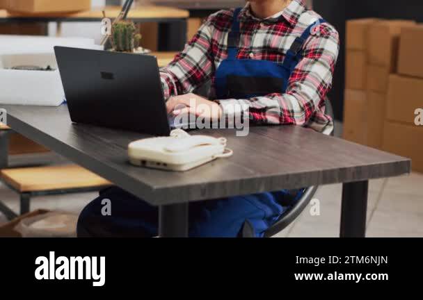 Young person doing warehouse inventory with pc, organizing products in ...