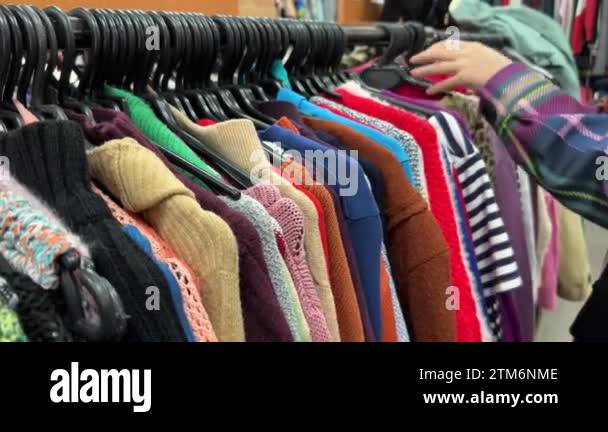 Woman hand chooses clothes in a second-hand shop. Thrift store hangers ...