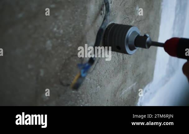 The drill is broken. A male worker is drilling a socket in the wall ...