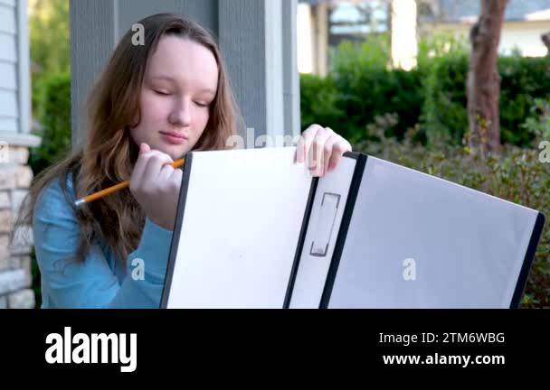 teenage girl with big white folder in hands crosses out something with ...