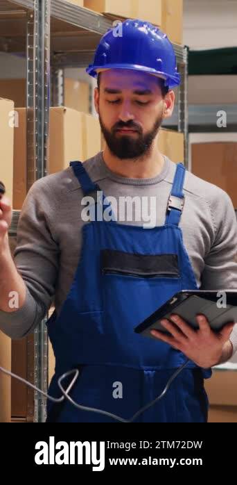 Vertical video: Young adult scanning barcodes on boxes in warehouse ...