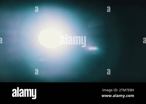 Point light of a bright flashlight directed at the camera on black ...