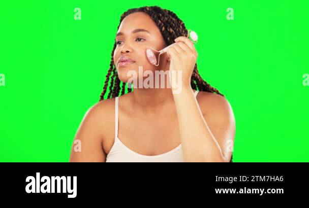 Woman, face roller and skincare on green screen, studio and crystal ...