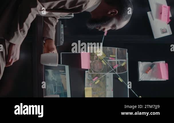Vertical video: Detectives team looking at evidence board on wall ...