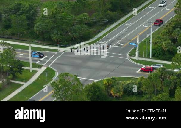 Suburban road with driving vehicles at intersection with traffic lights ...