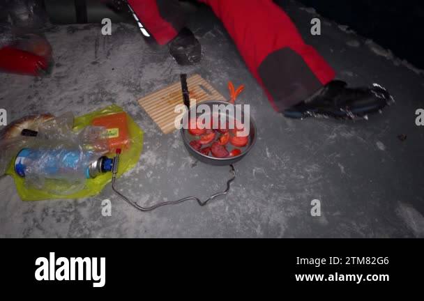 A guy cooks food on gas inside an ice cave. The climber lights the ...