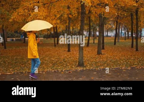 girl with yellow umbrella Slow motion rain city park. side view young ...