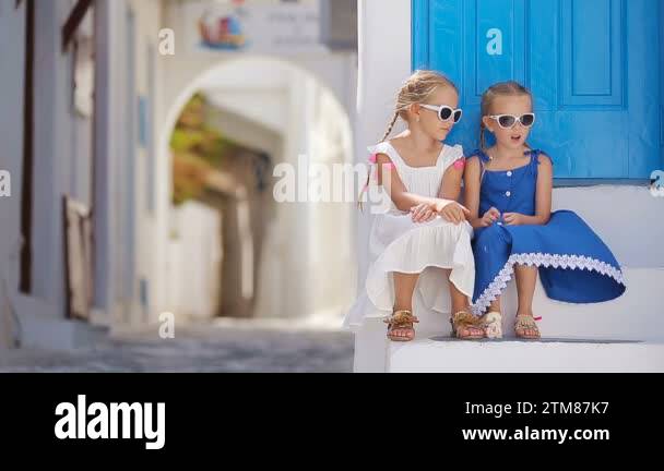 Two girls in blue dresses having fun outdoors. Kids at street of ...